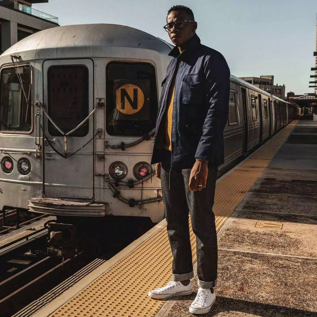 Home negre amb jaqueta de camp de Taylor Stitch a l'andana del metro.