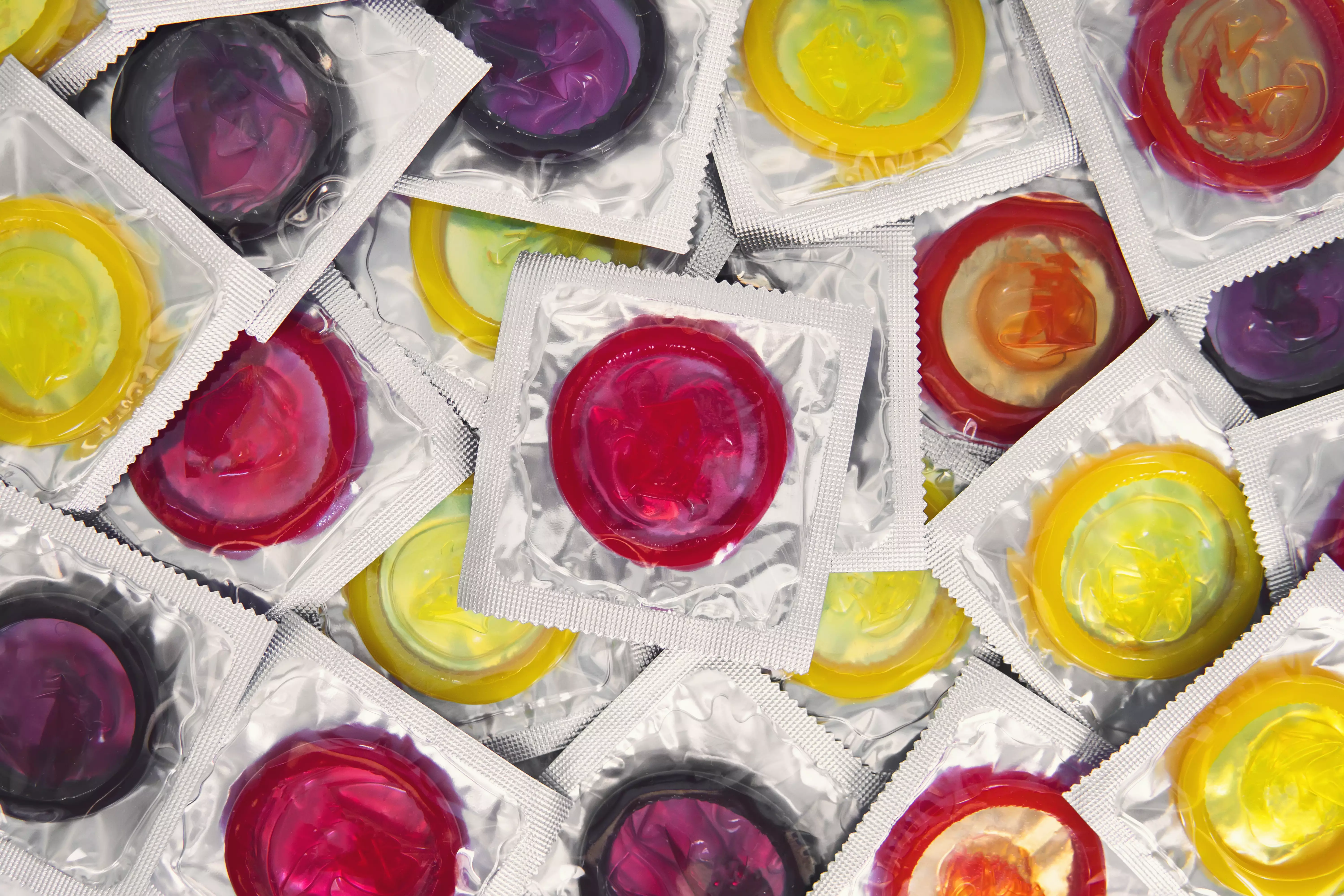 Farebný kondóm na pozadí. veľké množstvo kondómov. Koncept bezpečného sexu. veľa gumených kondómov. kopa predmetov