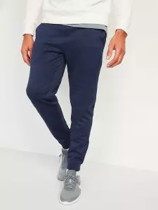 Man met witte trui, blauwe hardloopjoggingbroek en grijze sneakers