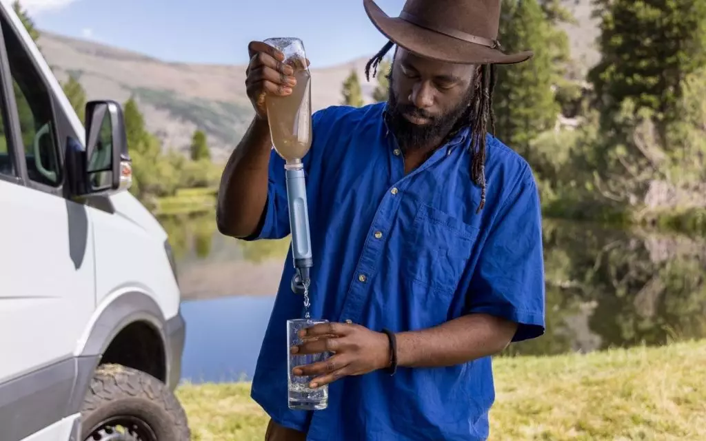 cilvēks filtrē ūdeni ar LifeStraw