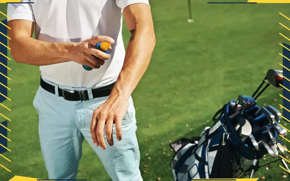 човек са палицама за голф који прска крему за сунчање
