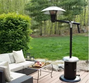 Cuisinart Perfect Position Outdoor Patio Heater អង្គុយនៅខាងក្រៅក្នុងទីធ្លាដែលមានស្មៅ និងរុក្ខជាតិបៃតងនៅផ្ទៃខាងក្រោយ