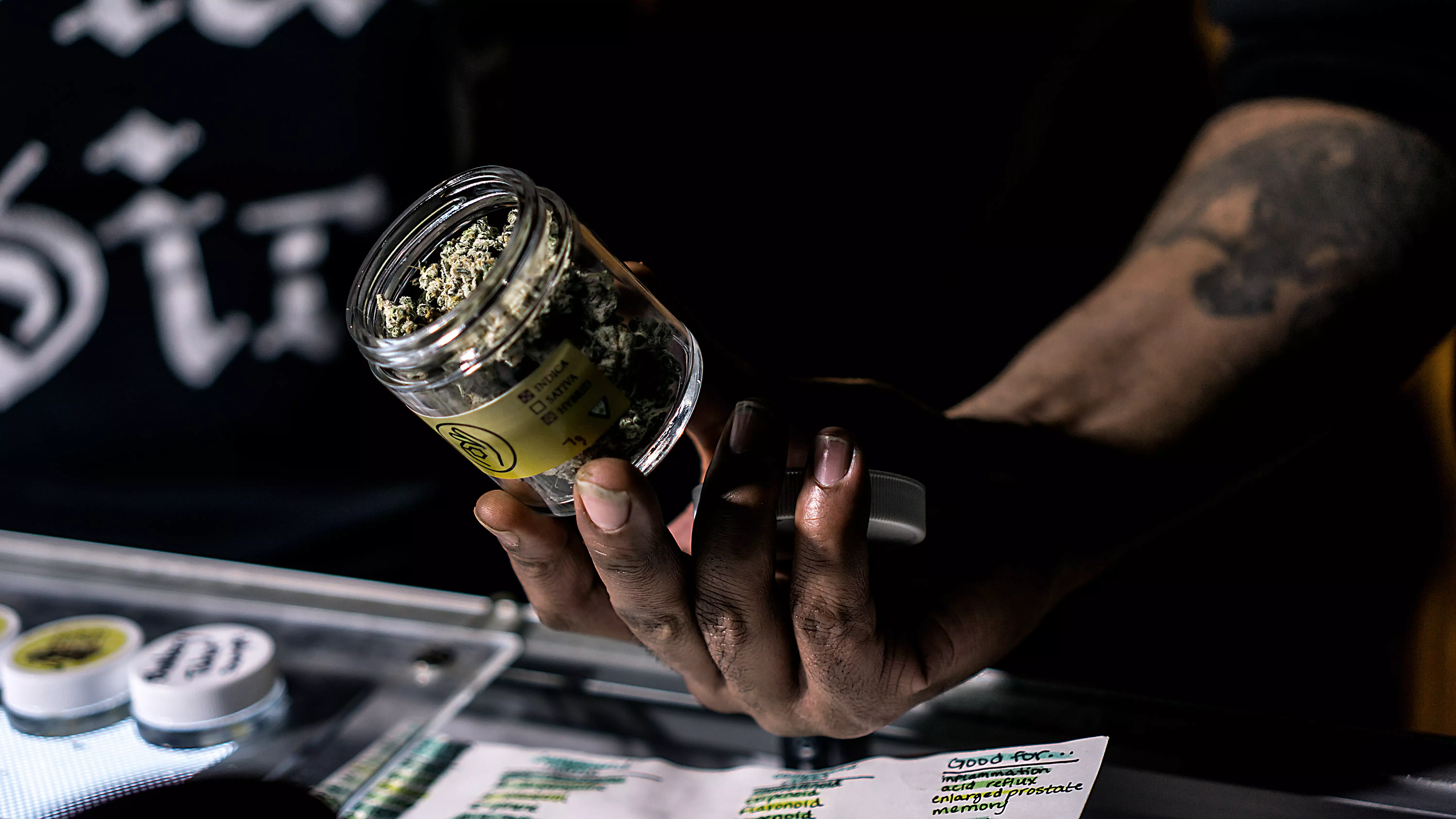 Un vendedor mostrando un frasco de flores de cannabis