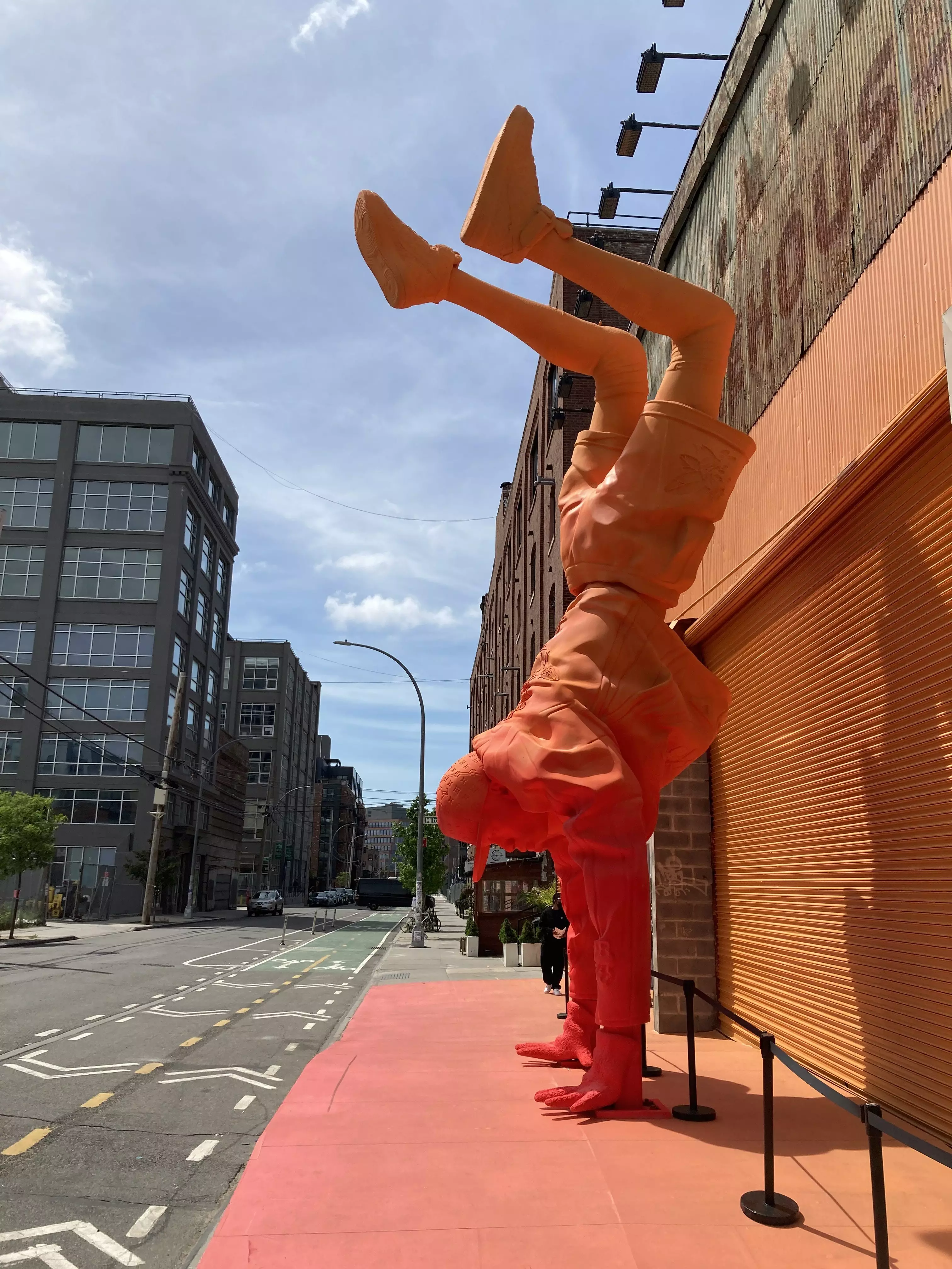 Estatua laranxa facendo unha parada de mans fóra do Virgil Abloh Memeorial en Brooklyn Nova York