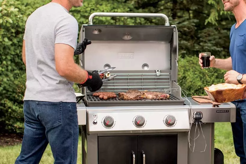 Multiple Männer grillen dobaussen op engem