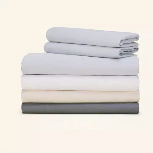 सबसे अच्छी कूलिंग शीट, क्रीम की पृष्ठभूमि पर चार रंगों में चादरों का ढेर