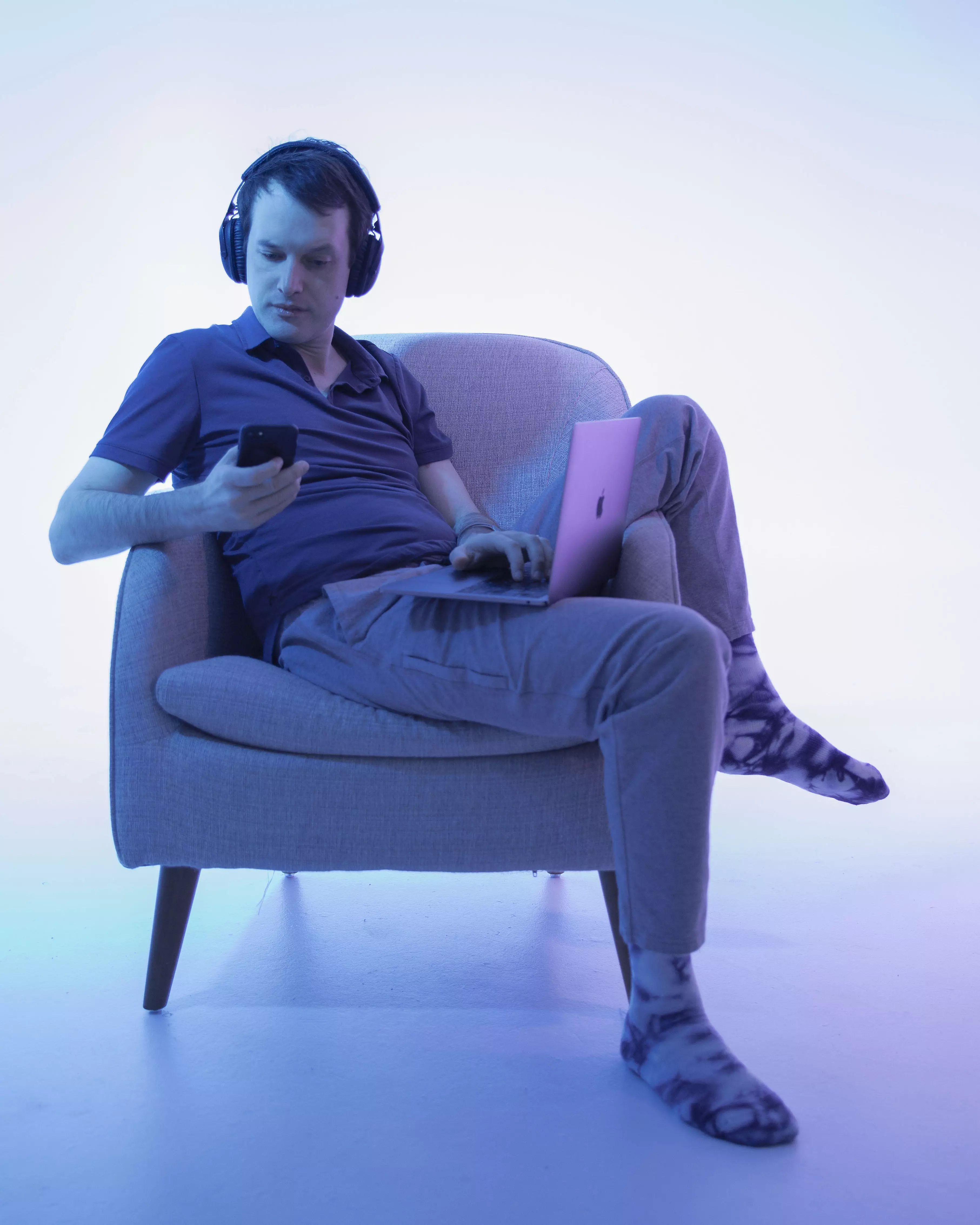 manlik model siet op stoel en wurket oan tillefoan en laptop, man prizen 2020