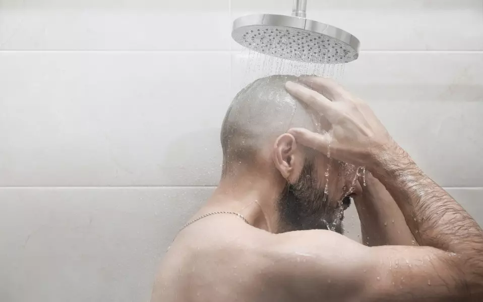 En mann vasker seg i dusjen.